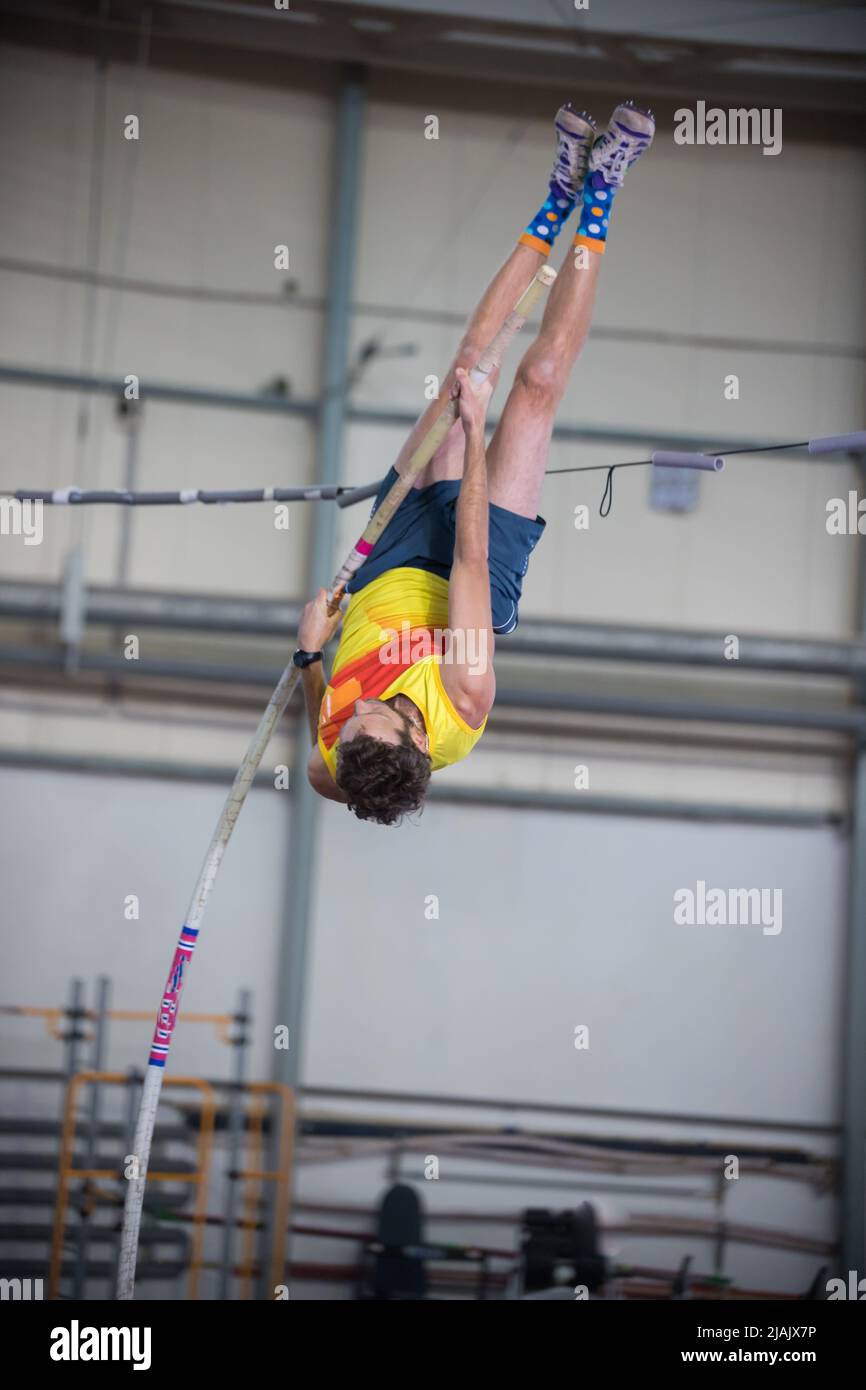 Pole vaulting indoors - a man jumping over the bar Stock Photo - Alamy