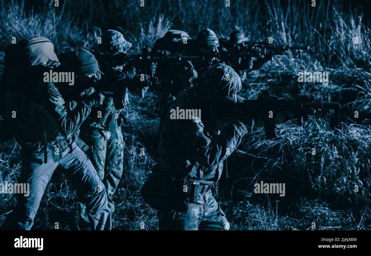 Special forces group aiming their rifles while on a night patrol ...