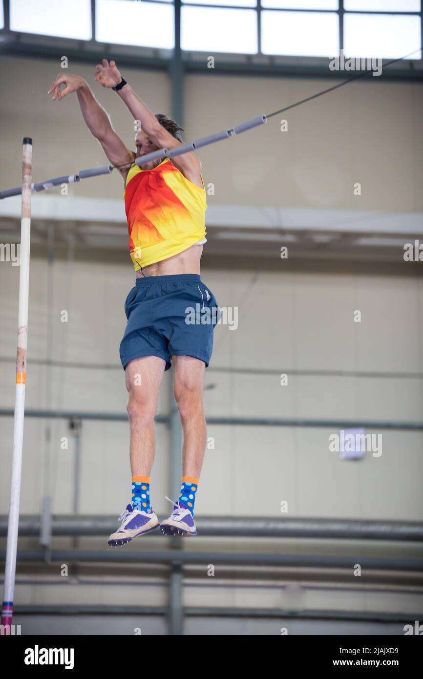 Pole vaulting indoors - a man falling down after jumping over the bar ...