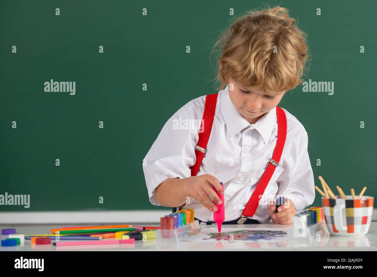 Child boy drawing cute draw using colored pencils at school or ...