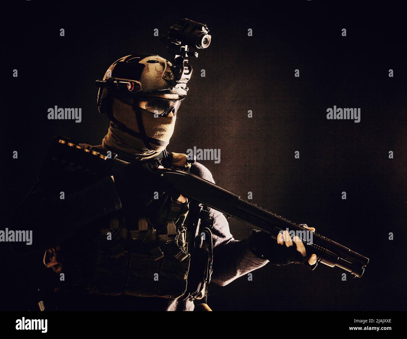 Low key studio shot of an elite soldier with shotgun, wearing face mask ...