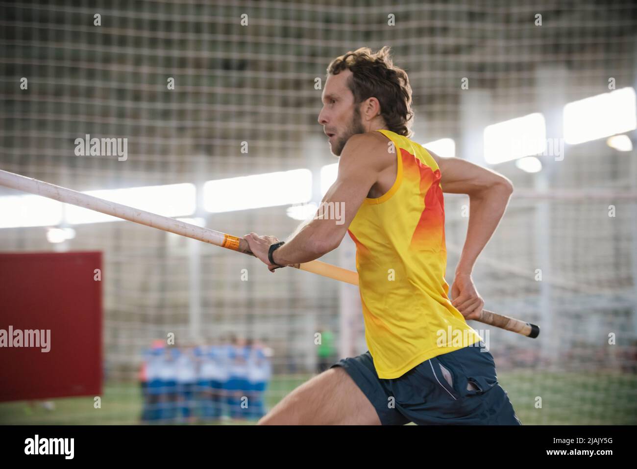 Pole vaulting indoors - a athletic man running on the track with a pole ...