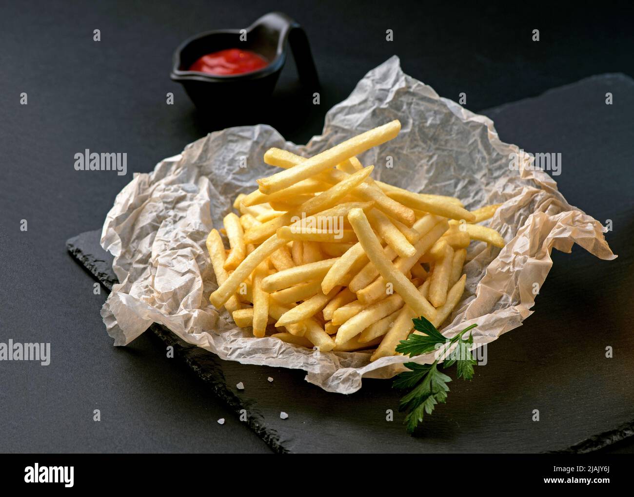 Pile of french fries placed on food oil blotting paper on black plates ...