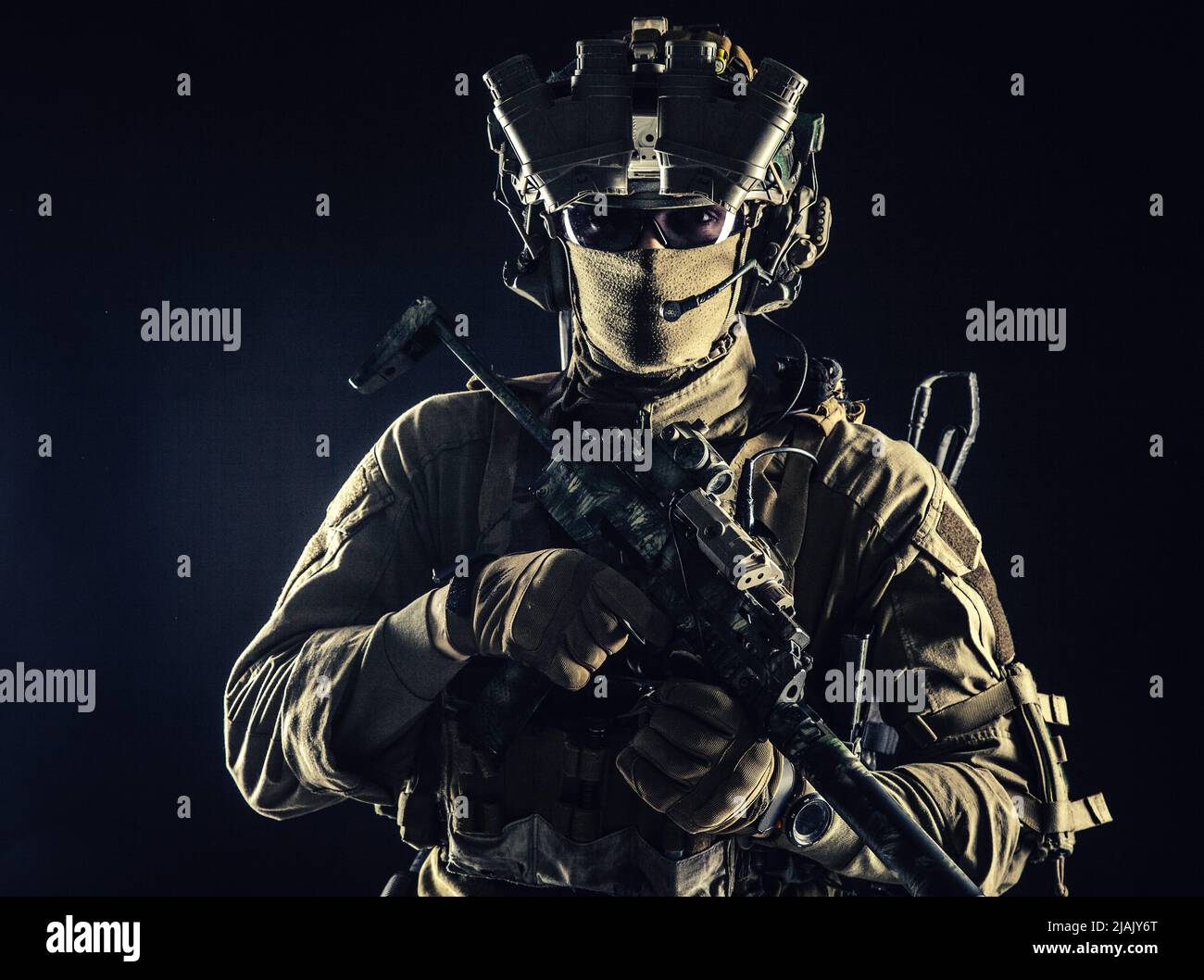 Serviceman equipped with modern weapons, studio portrait on black ...