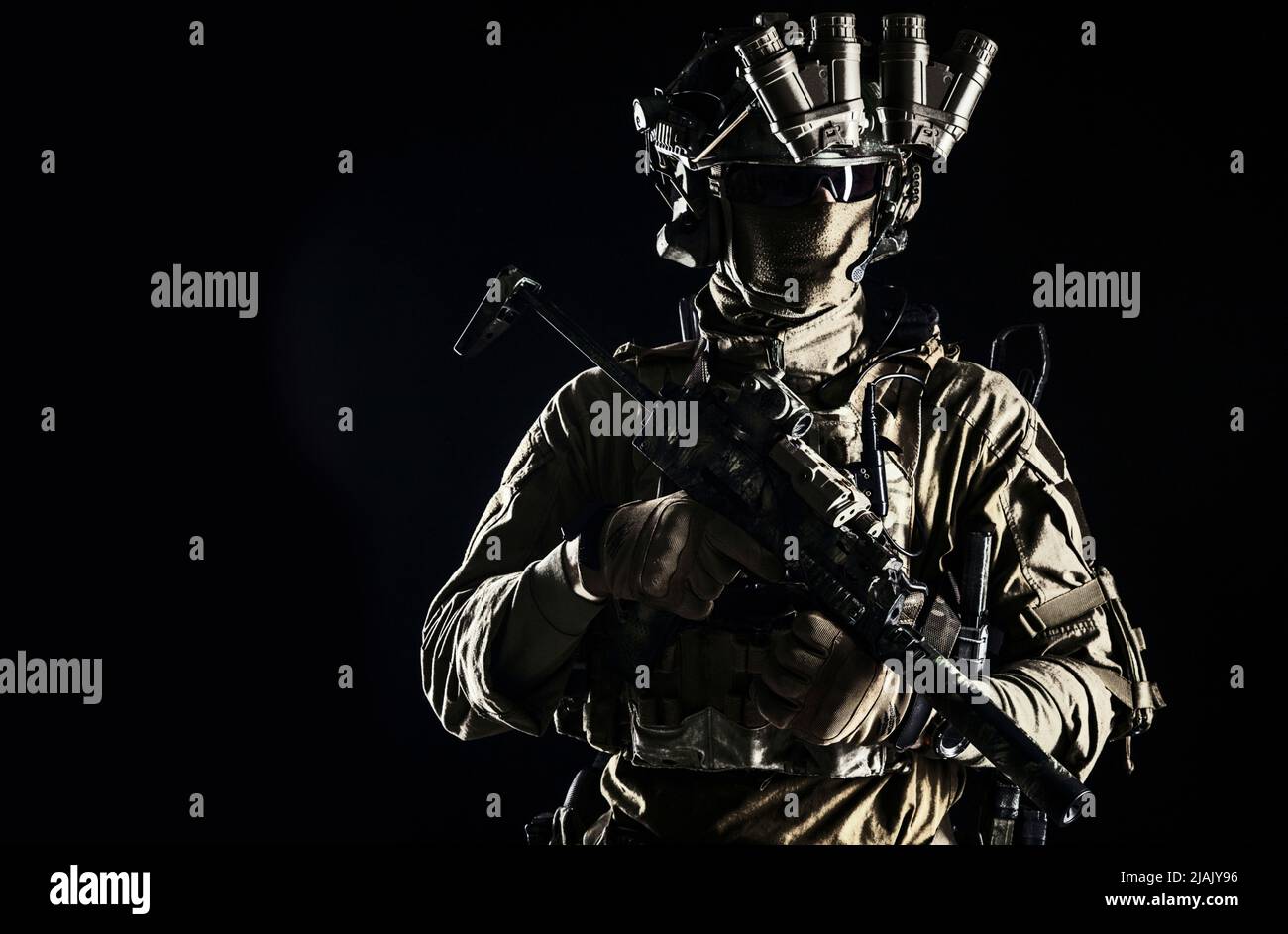 Serviceman equipped with modern weapons, studio portrait on black ...