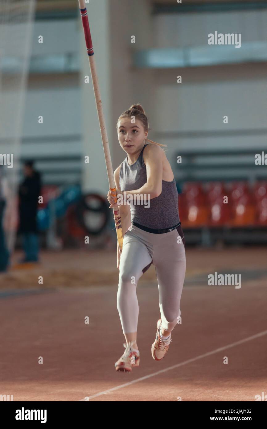 Pole vaulting indoors - young pretty sportive woman running with a pole ...