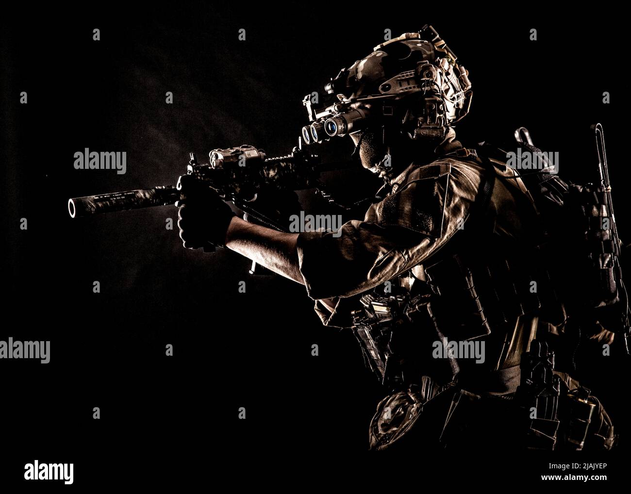 A special operations soldier wearing night vision device, aiming short ...