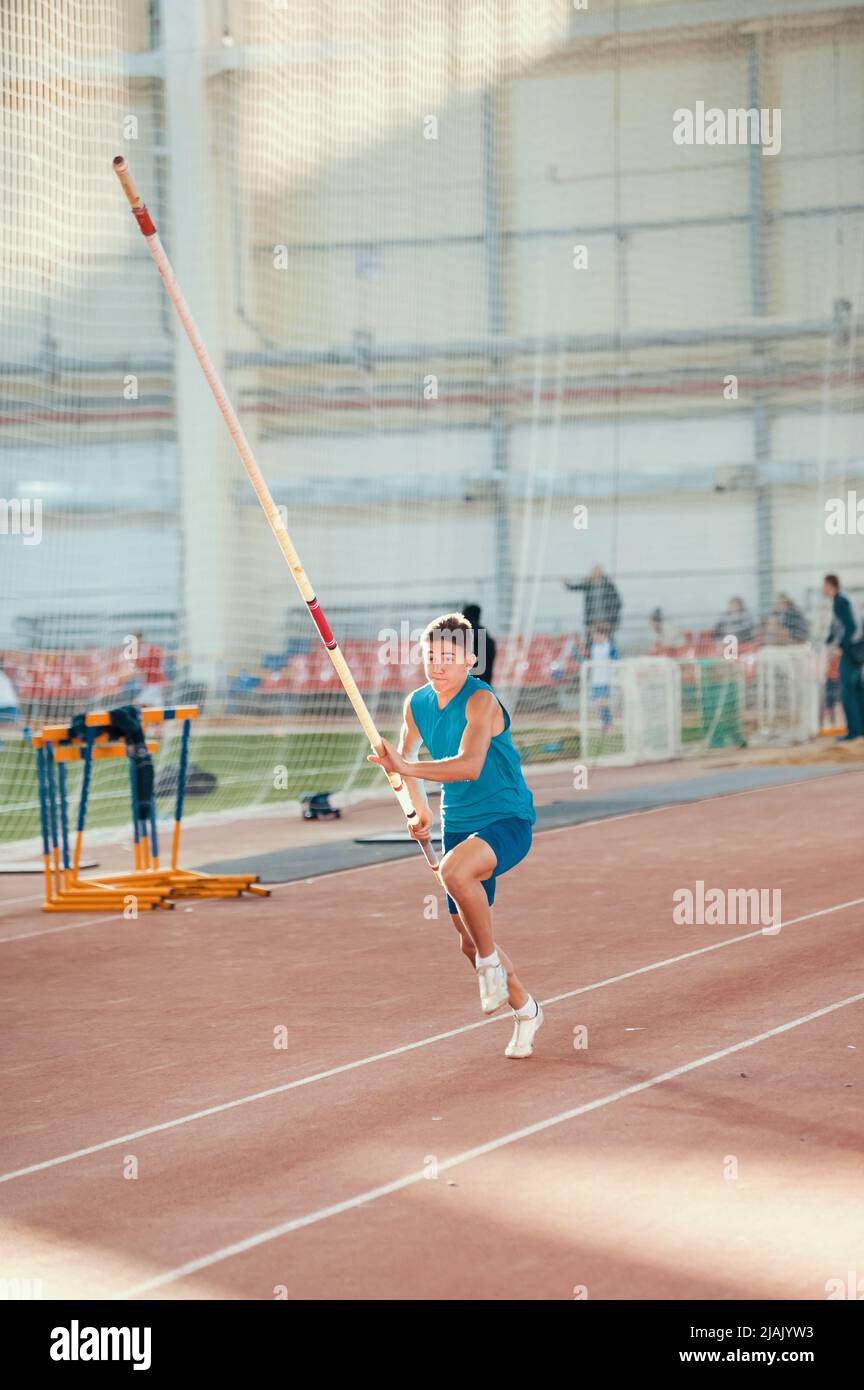 Pole vaulting indoors - young man in blue shirt running up before ...