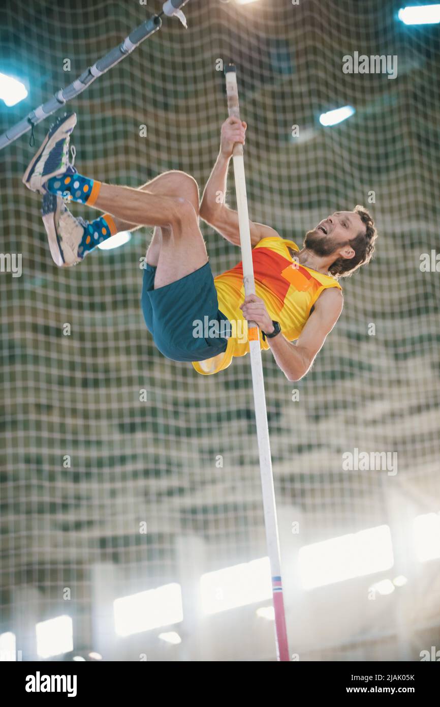 Pole vaulting in the sports stadium - an athletic man jumping over the ...