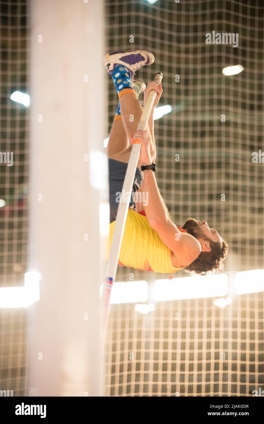 Pole vaulting in the sports stadium - an athletic man jumping over the ...