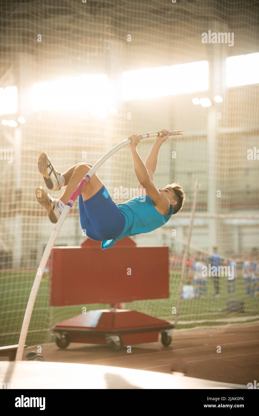 Pole vault training in the sports stadium - young fit man jumping over ...