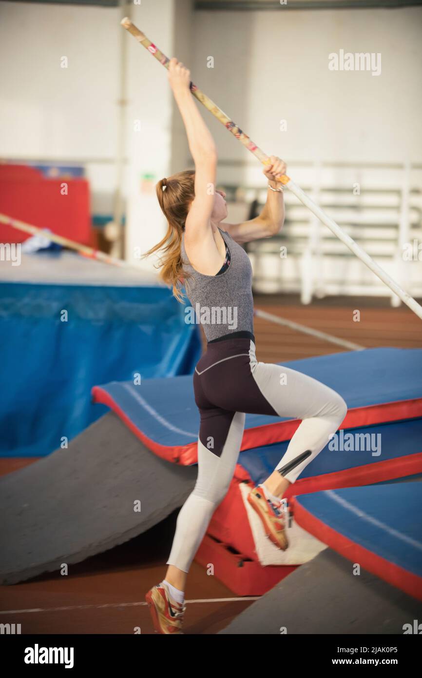 Pole vaulting in the sports stadium - young sportive woman with ...