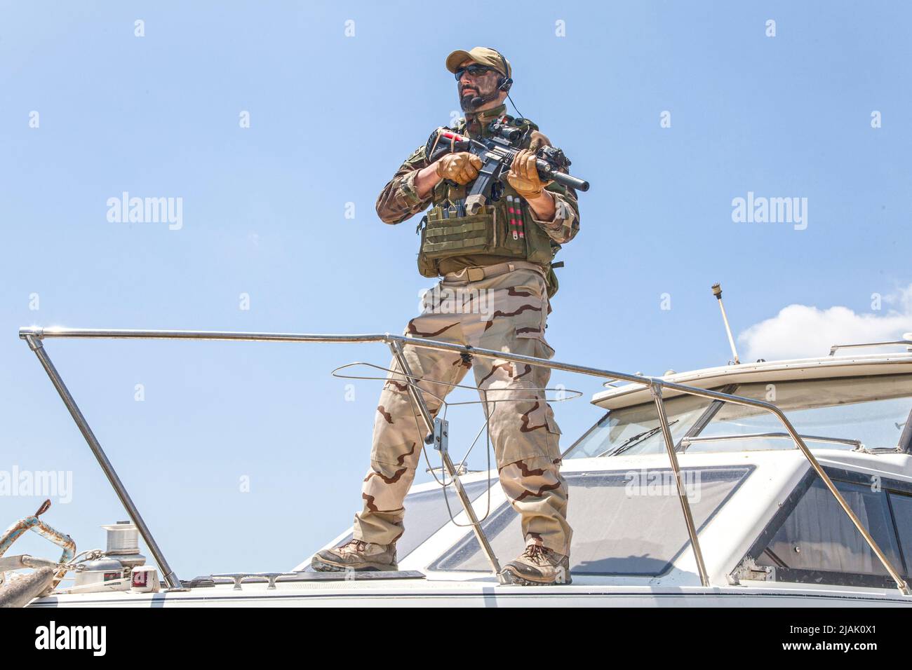 Special forces soldier armed with rifle, standing on bow of a speed ...