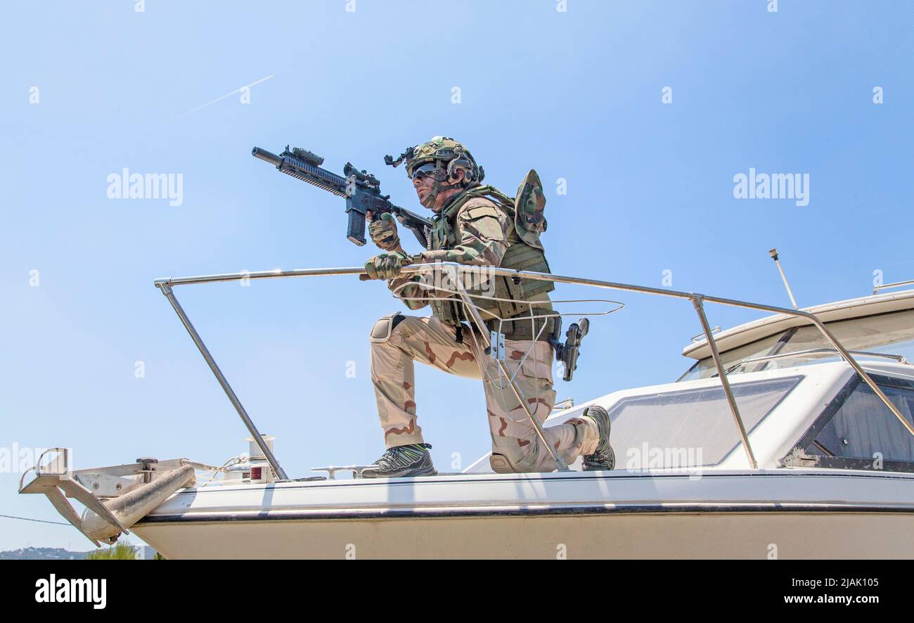 Special forces soldier armed with rifle, standing on bow of a speed ...