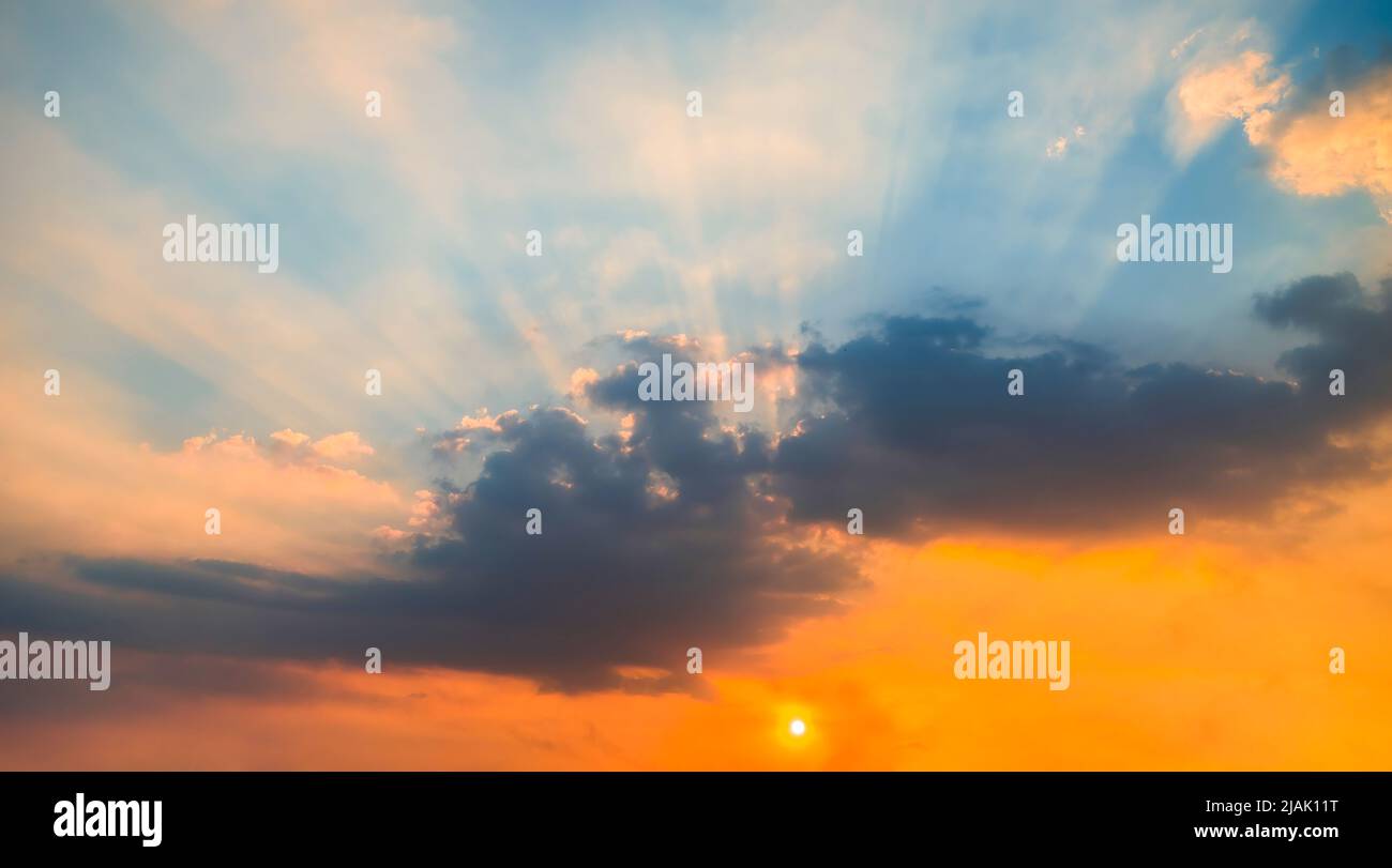 Blue and orange sunset sky with rays of sun. Sun rays slipping through ...