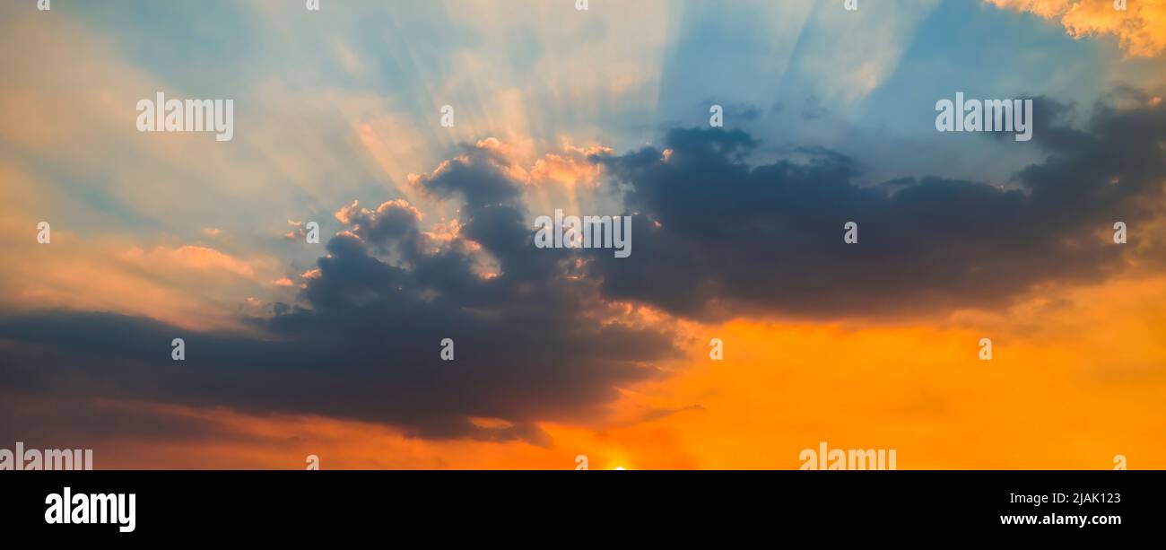 Blue and orange sunset sky with rays of sun. Sun rays slipping through ...