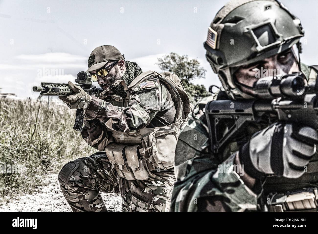 Soldiers kneeling in grass, aiming assault rifle with collimator sight ...