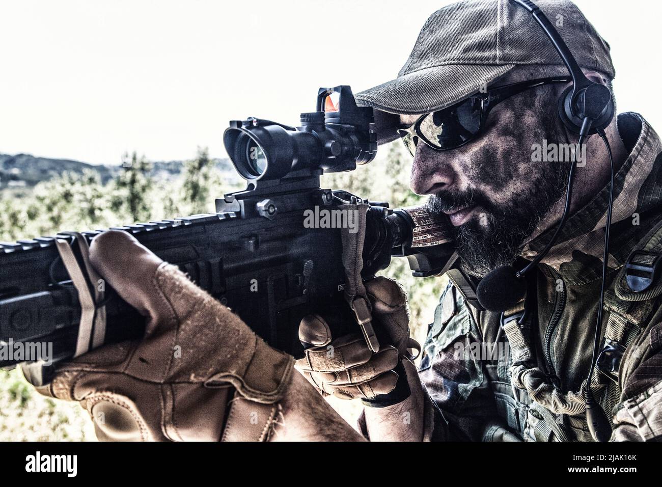 Modern combatant equipped with radio headset, looking through optical ...
