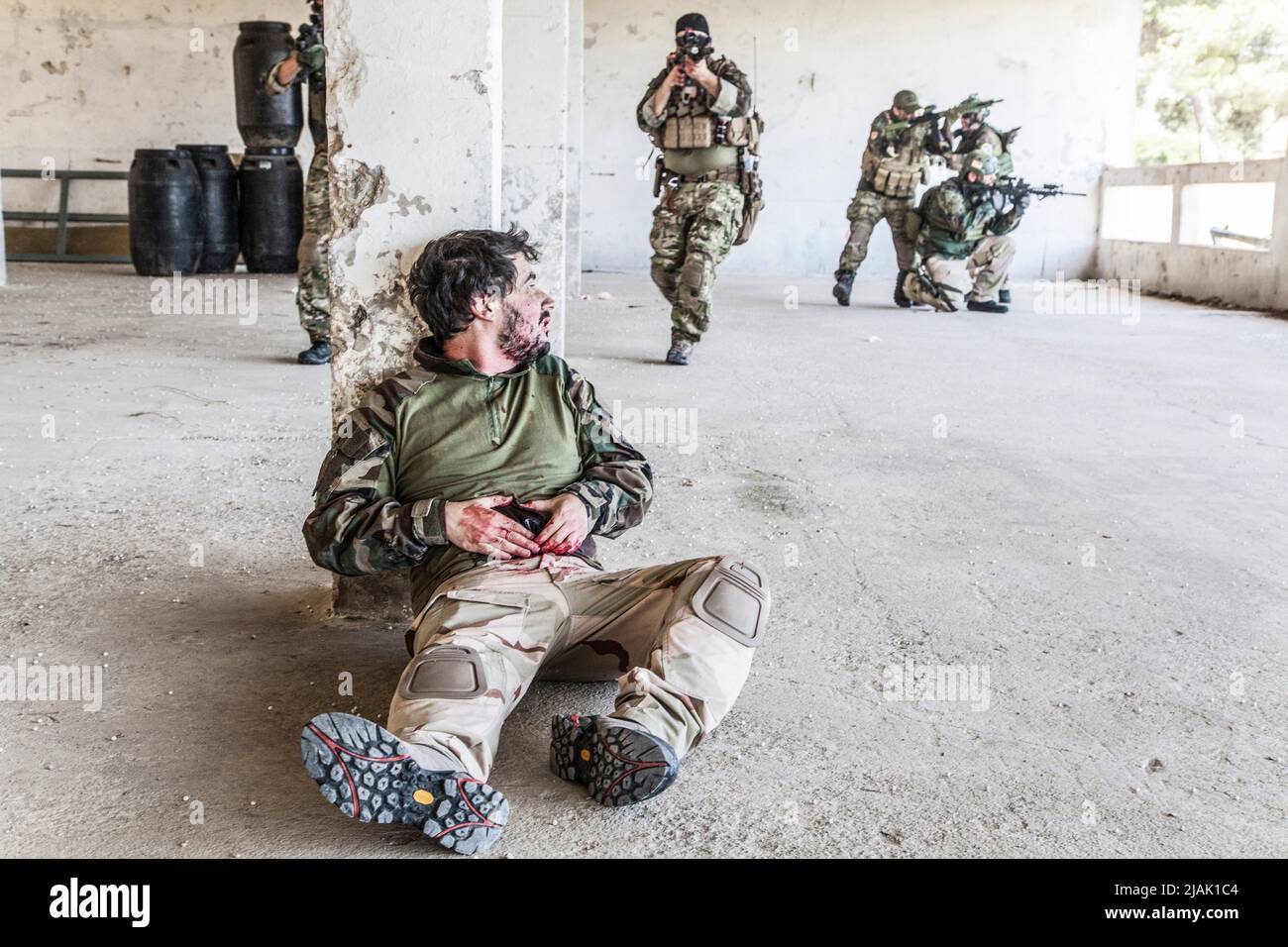 A wounded soldier sitting on floor behind a concrete column waiting for ...