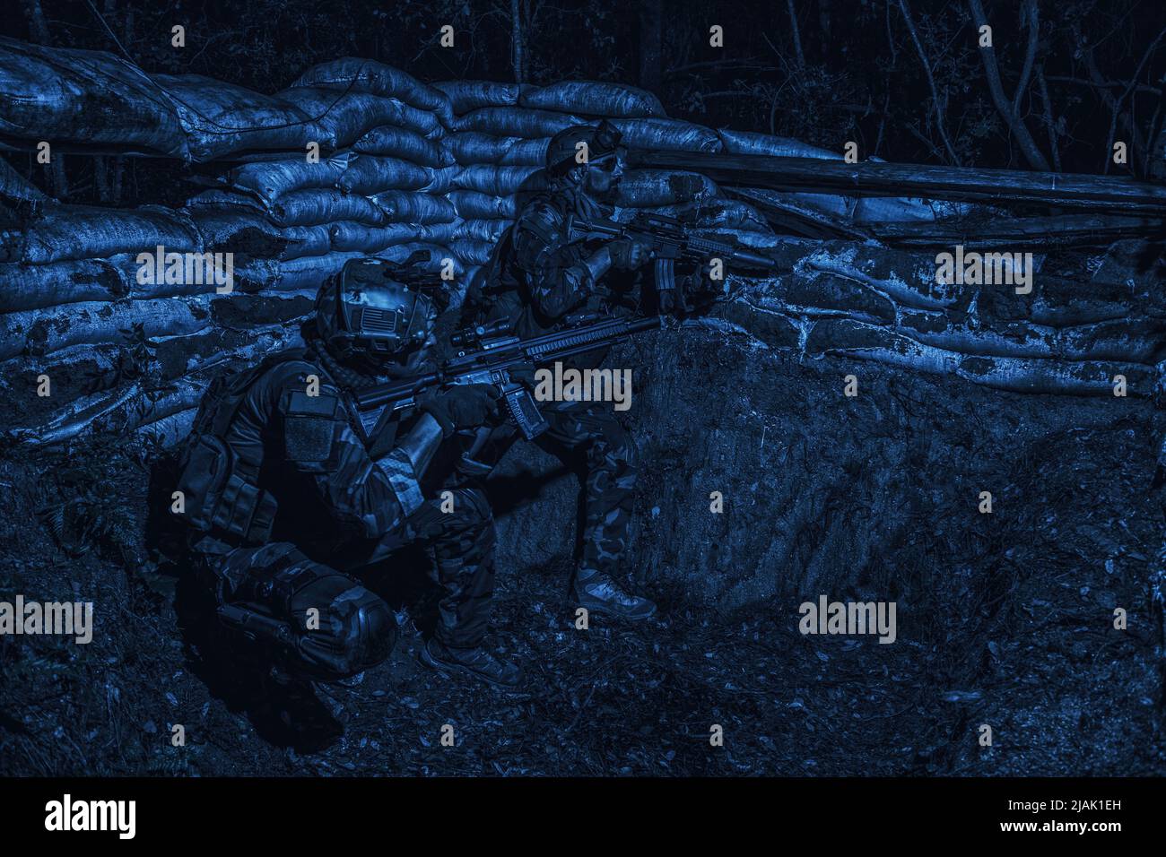 Soldiers take cover in a trench from enemy fire during a night attack ...