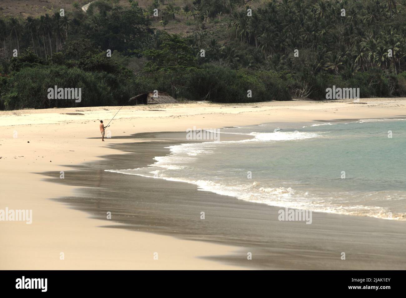 A man fishing with fishing rod from sandy beach of Rua in Wanokaka ...