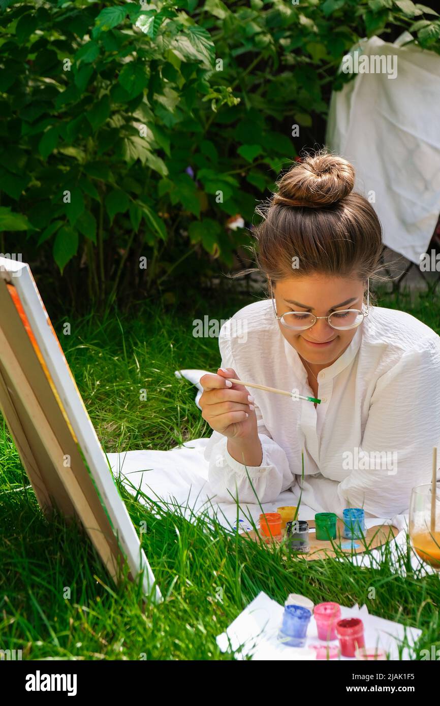 Artist painting on the easel outdoors in the garden. Open air outdoor ...