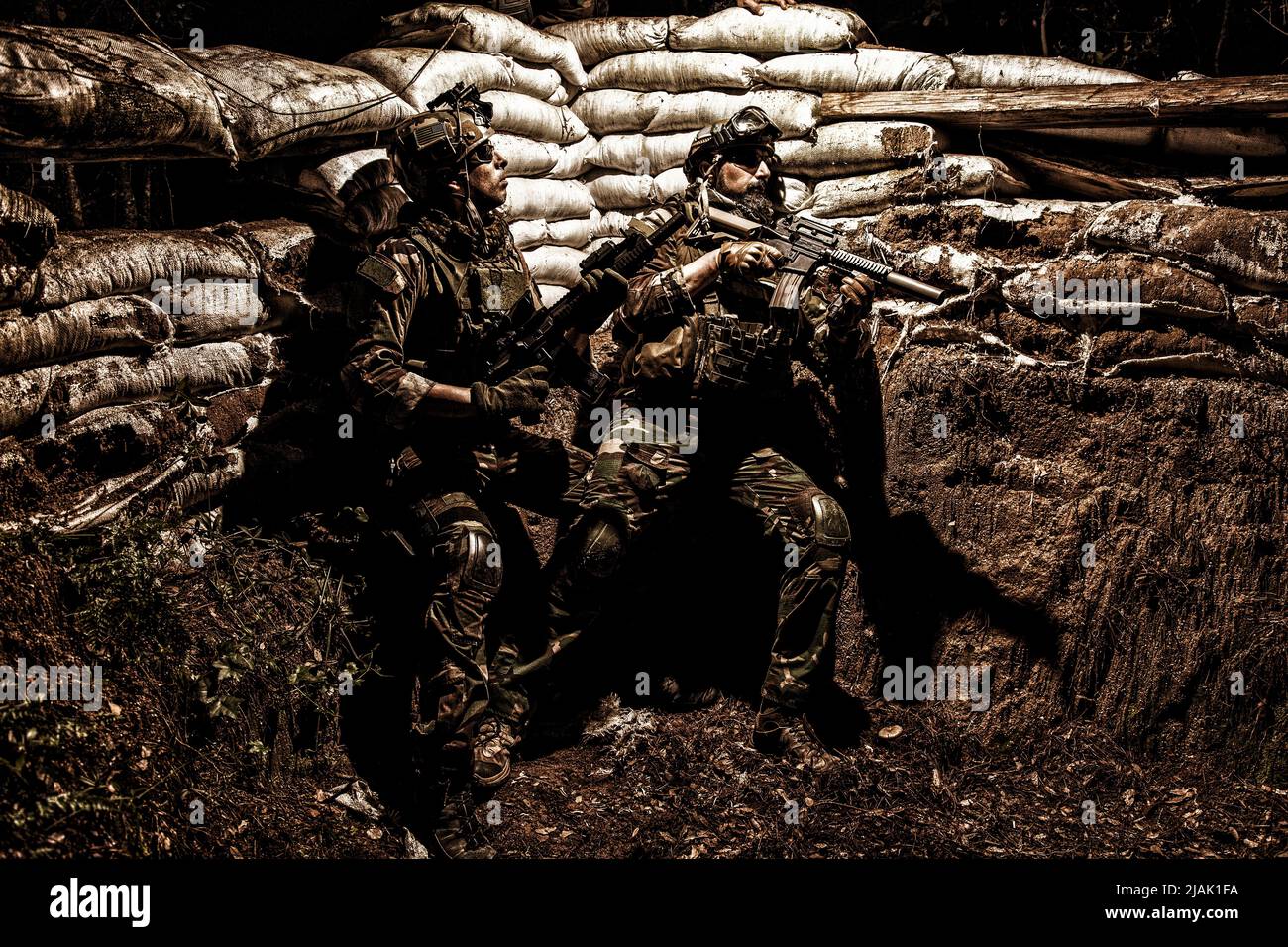 Soldiers take cover in a trench from enemy fire during a night attack ...