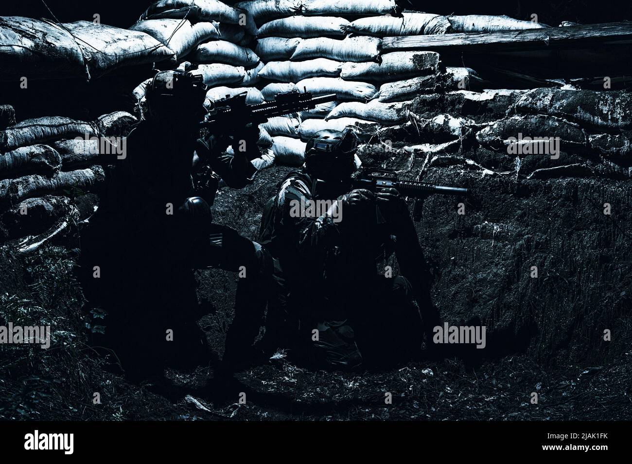 Soldiers take cover in a trench from enemy fire during a night attack ...