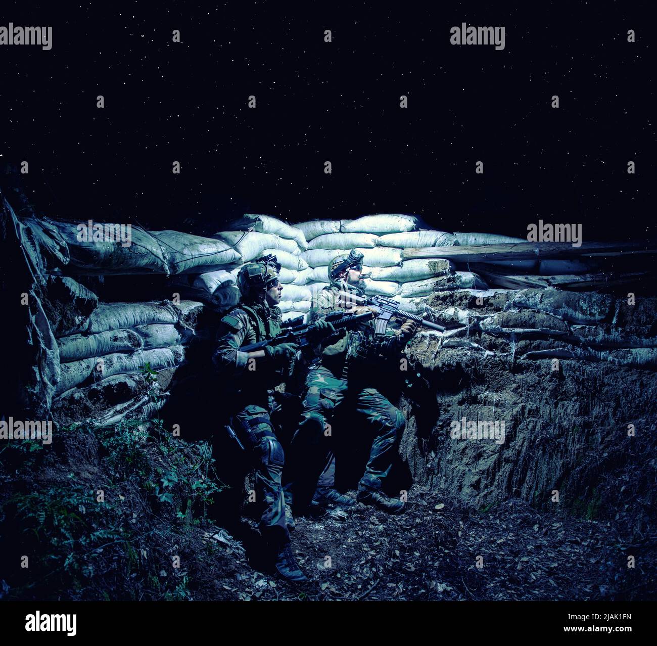 Soldiers take cover in a trench from enemy fire during a night attack ...