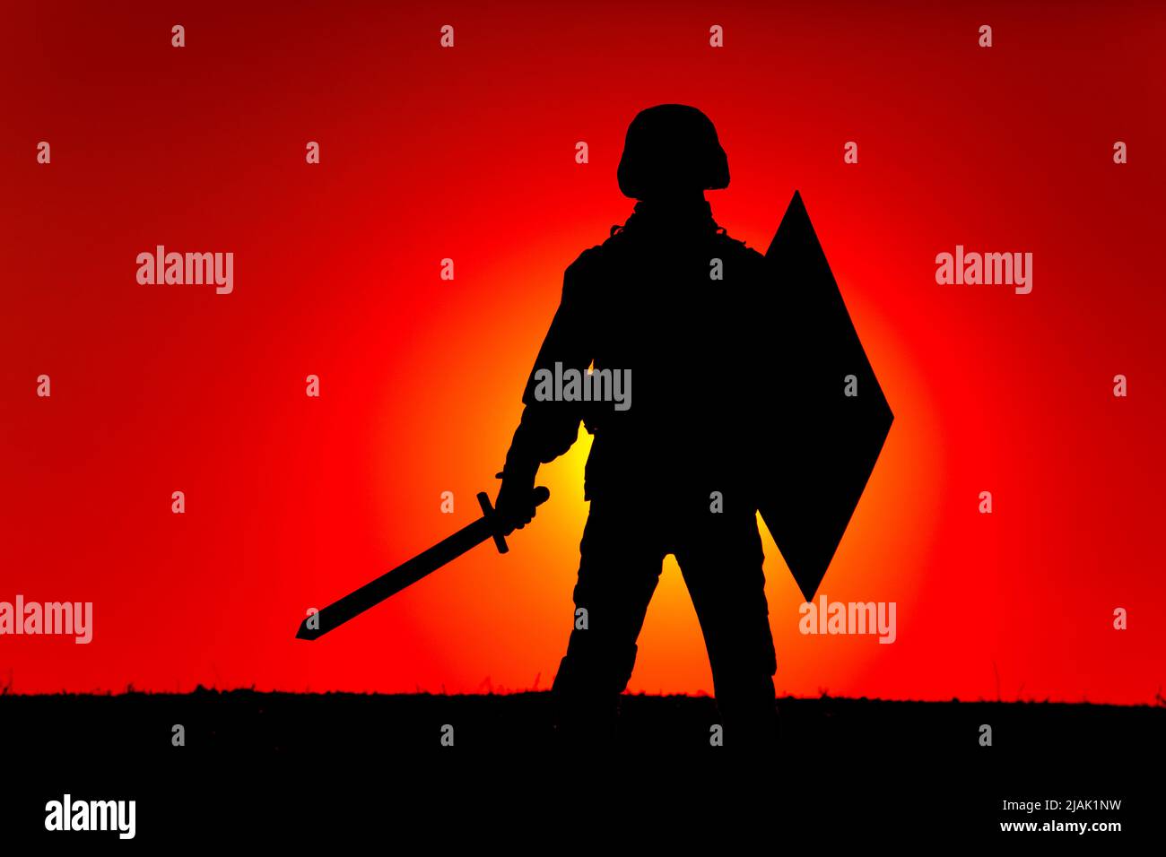 Silhouette of a soldier armed with sword and shield, with sun setting ...