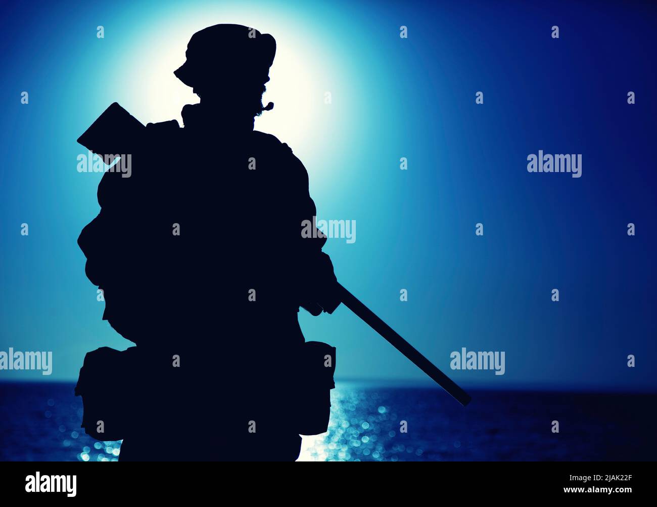 Silhouette of a sniper standing against blue sky while on a night ...