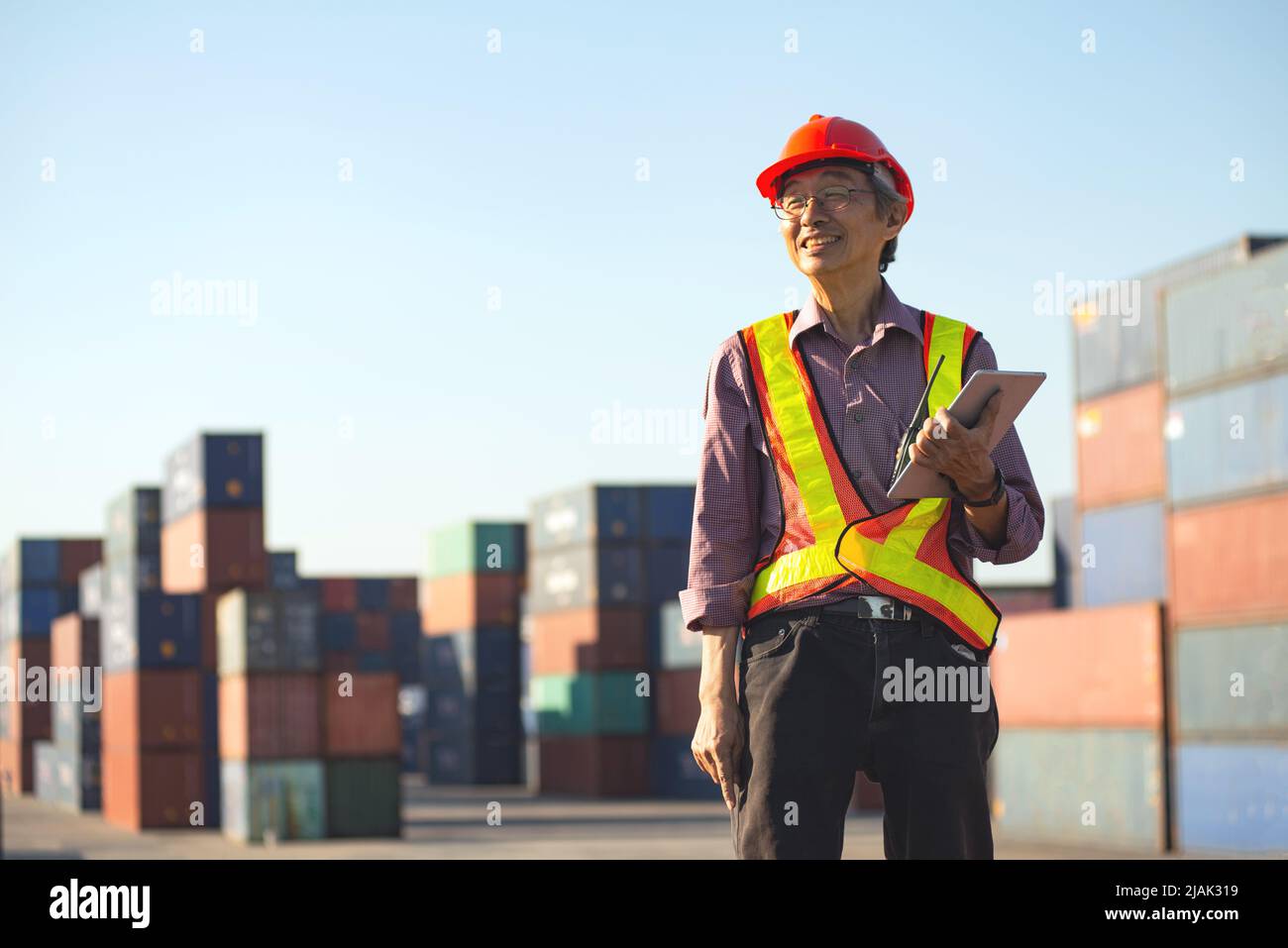 A senior elderly Asian worker engineer wearing safety vest and helmet ...