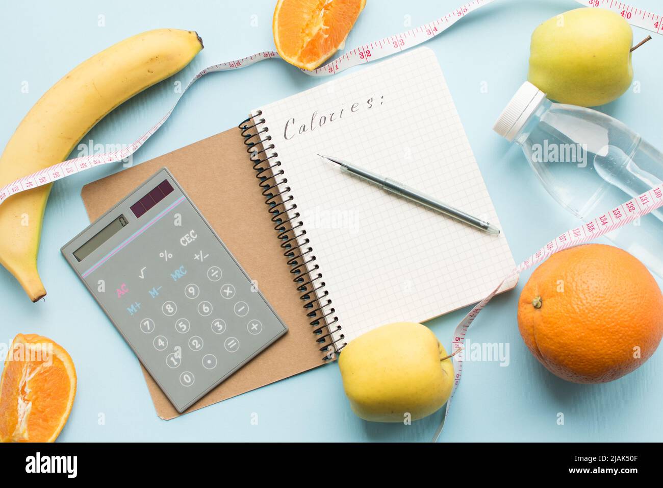 Paper notebook with word CALORIES, calculator, pen, bottle of water ...