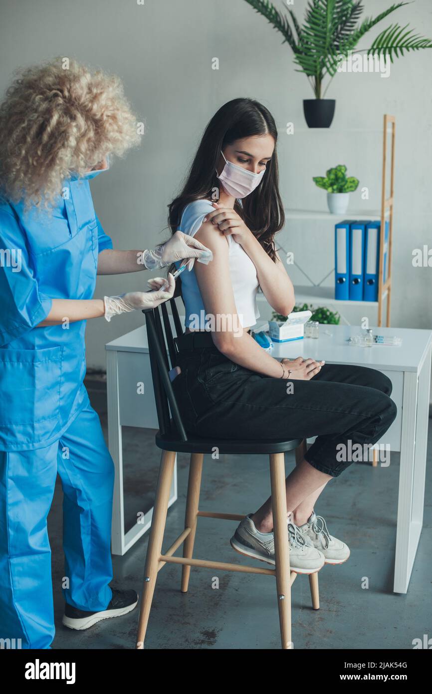 Woman getting vaccine from nurse giving syringe shot to arm's patient ...