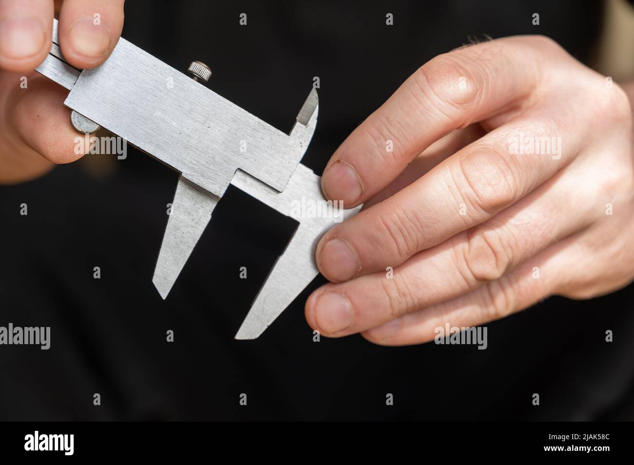 A man's hand holding a caliper. An adult man with a high-precision ...