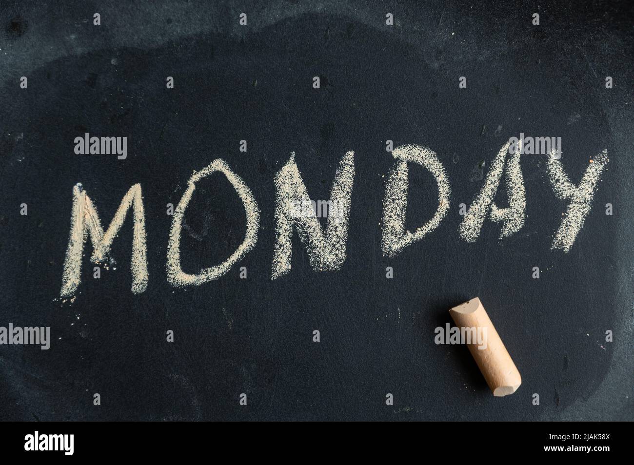 Monday. Name of the day of the week written in yellow chalk on a black ...