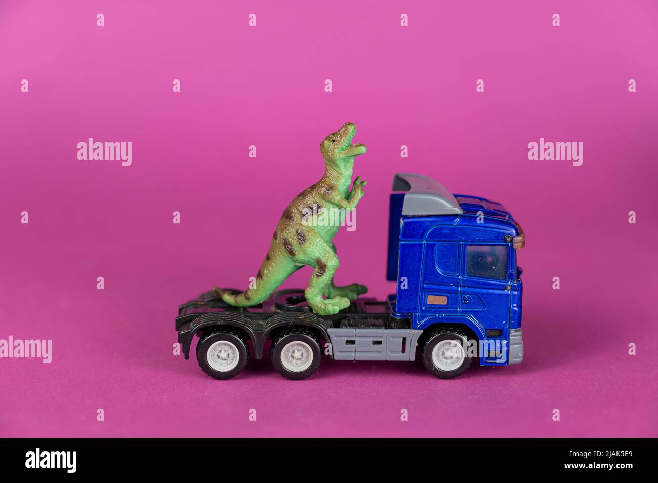 Dinosaur and tractor-trailer against a purple background. Green plastic ...