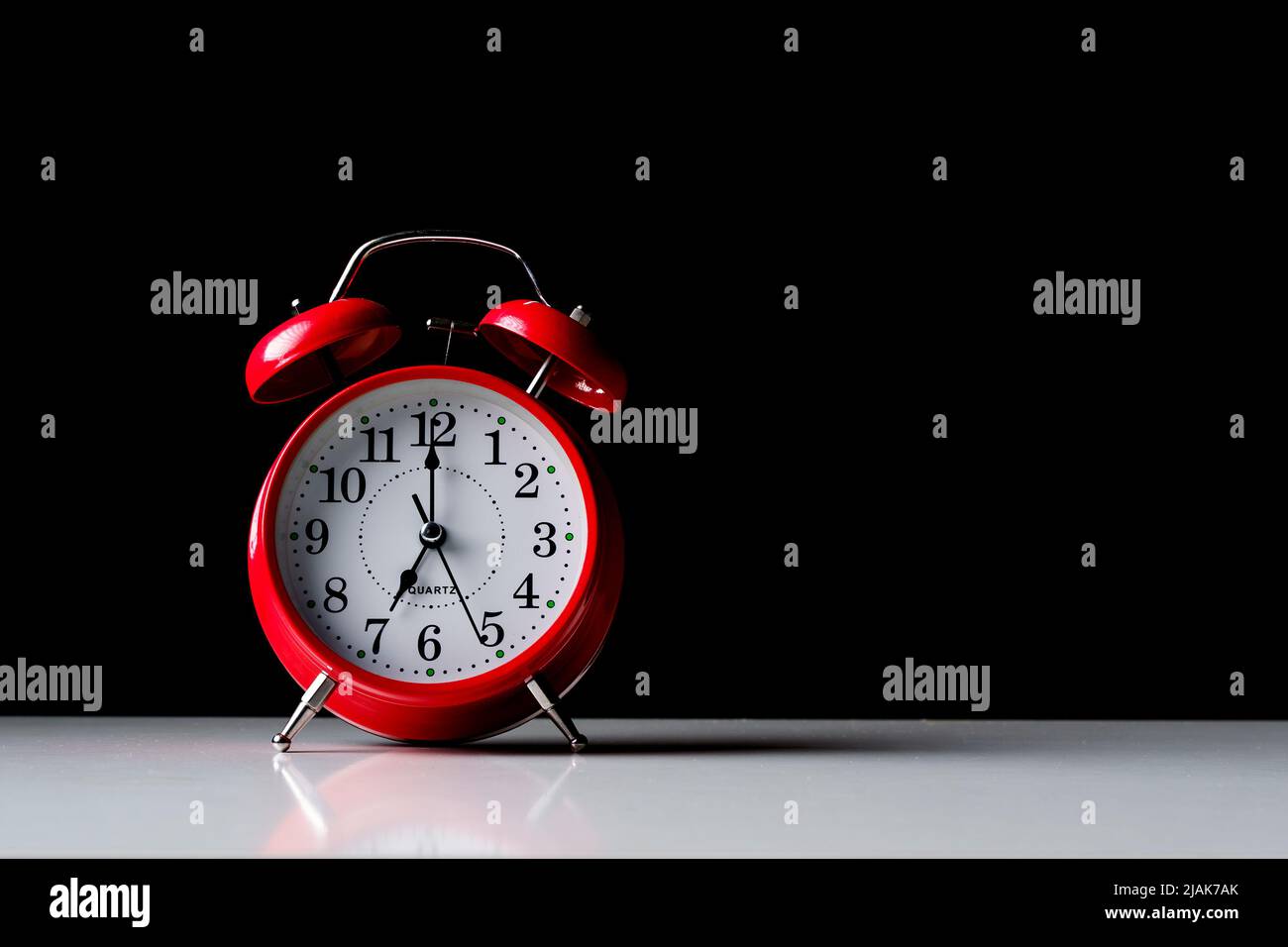 Red alarm clock on a white table with arrows at seven o'clock, black ...