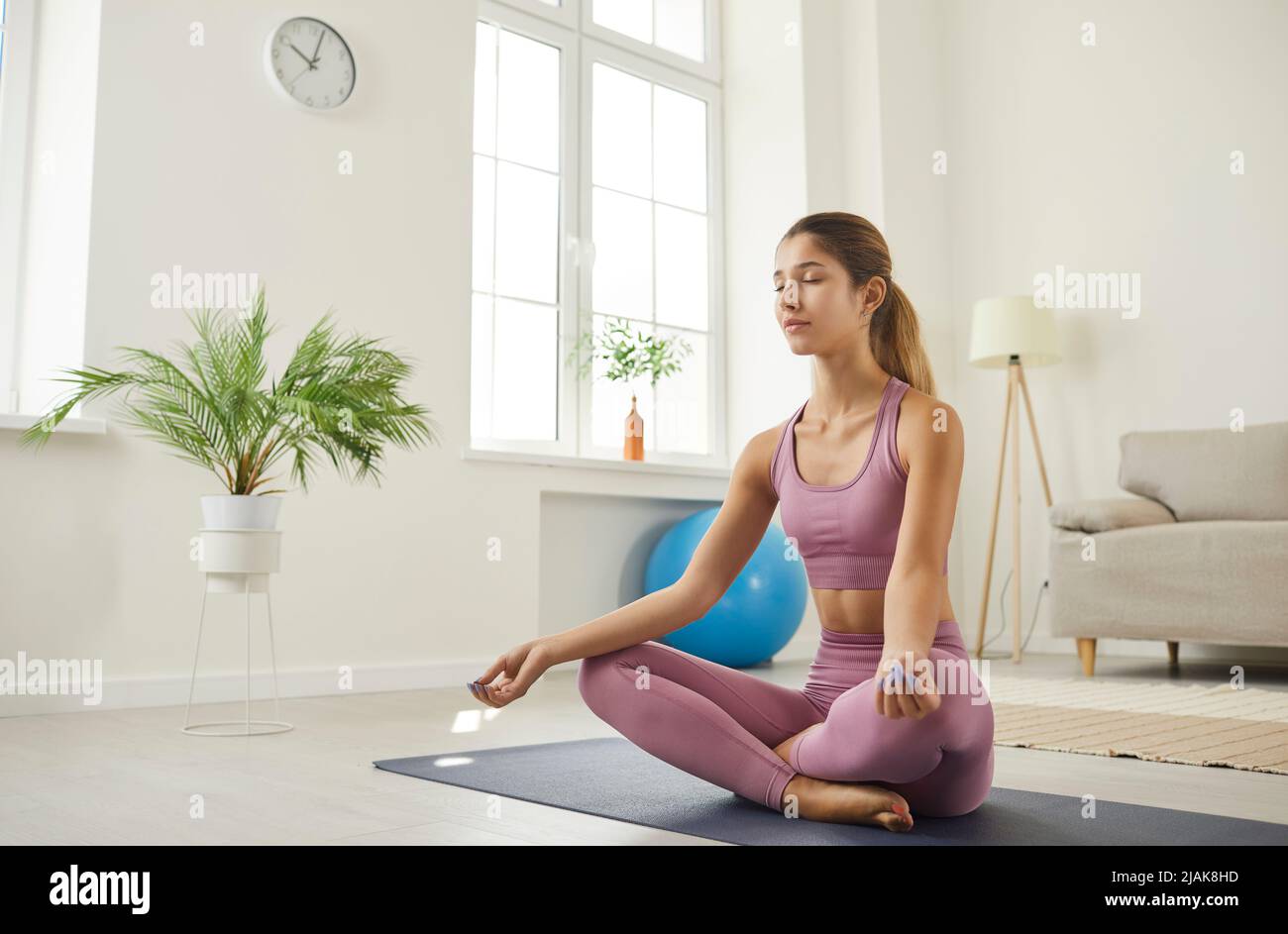 Relaxed and calm young woman at home practicing lotus asana sitting in ...