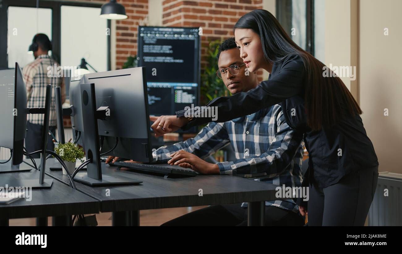 Two Programers Holding Laptop With Coding Interface Walking Towards Desk And Sitting Down