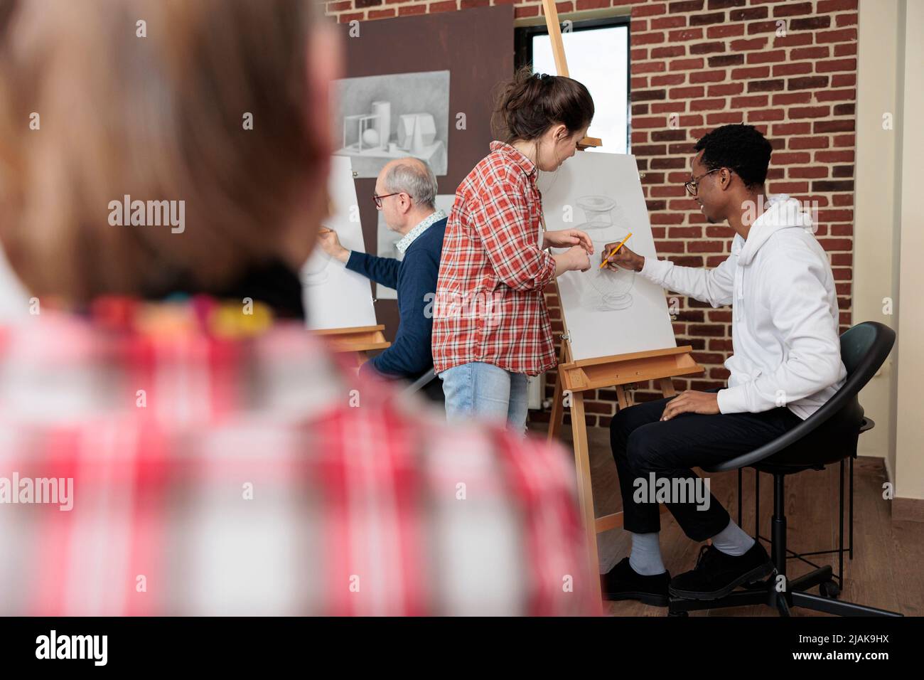 Artist teacher explaining drawing process to young student during ...
