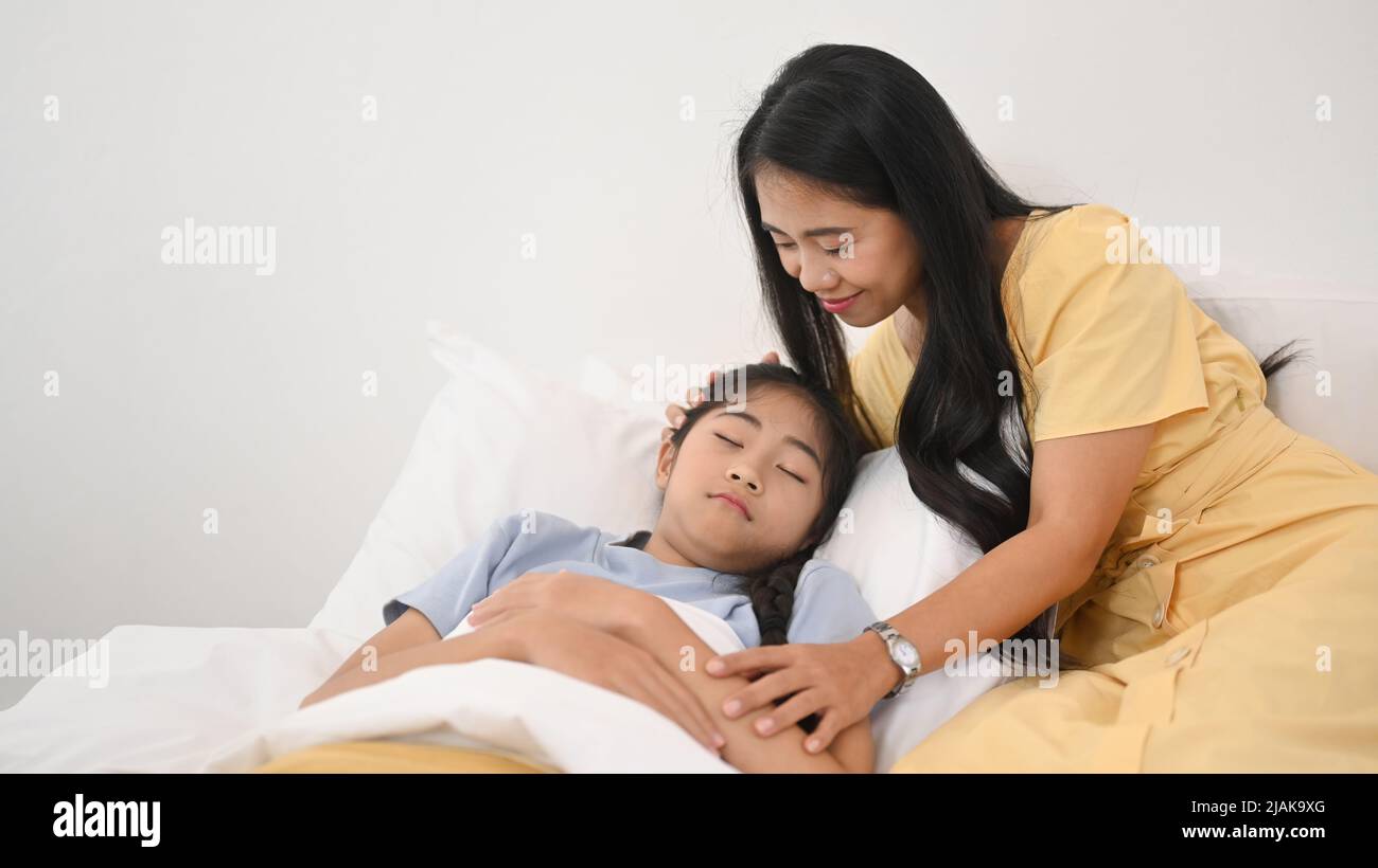 Loving mother taking care of her ill daughter with fever sleeping in ...
