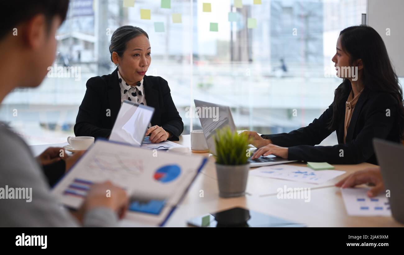 Experienced senior female team leader talking, giving instructions to ...