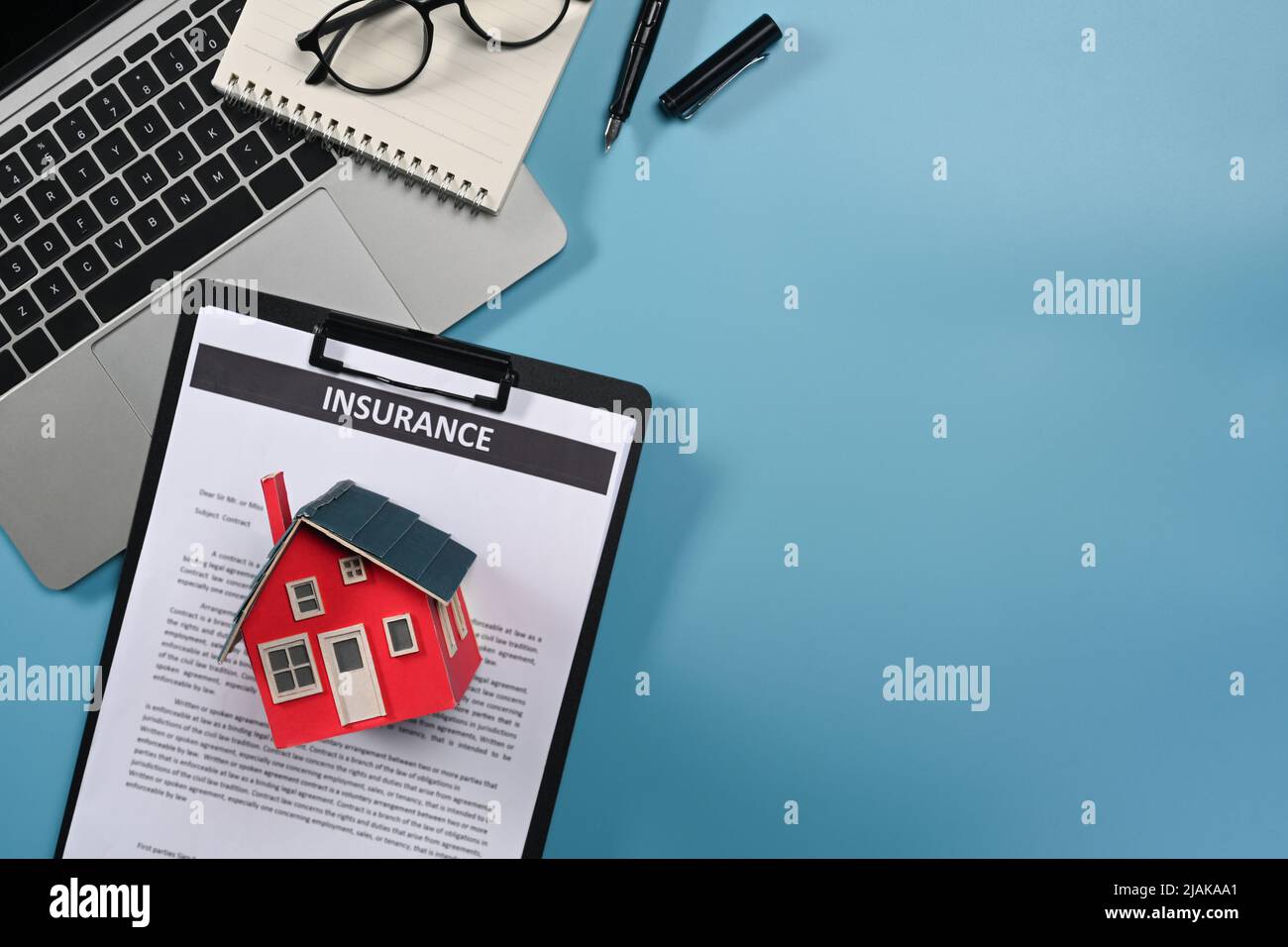 Top view laptop computer, house model ad notepad on blue background ...