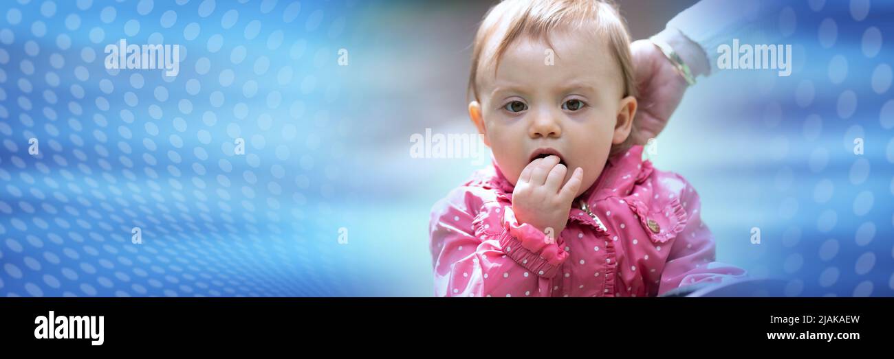 Portrait of cute baby girl eating a biscuit in playground; panoramic ...