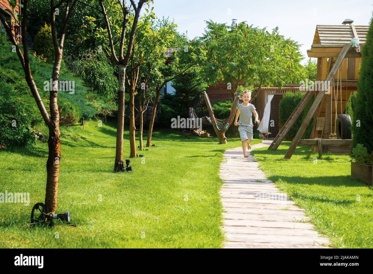 A little boy cheerfully runs along the path outside the city on a sunny ...