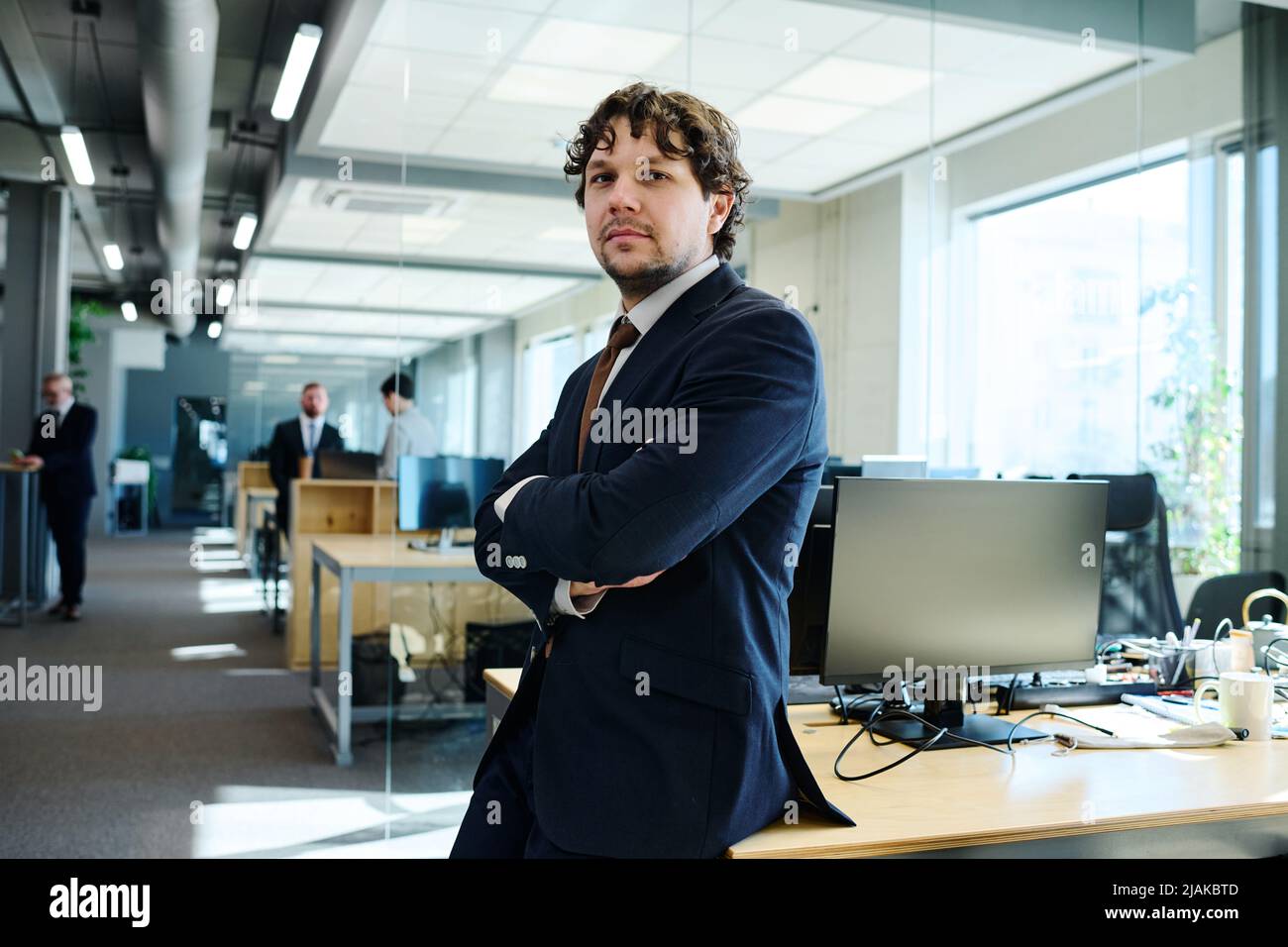Portrait of young office manager in formal suit leaning on his ...