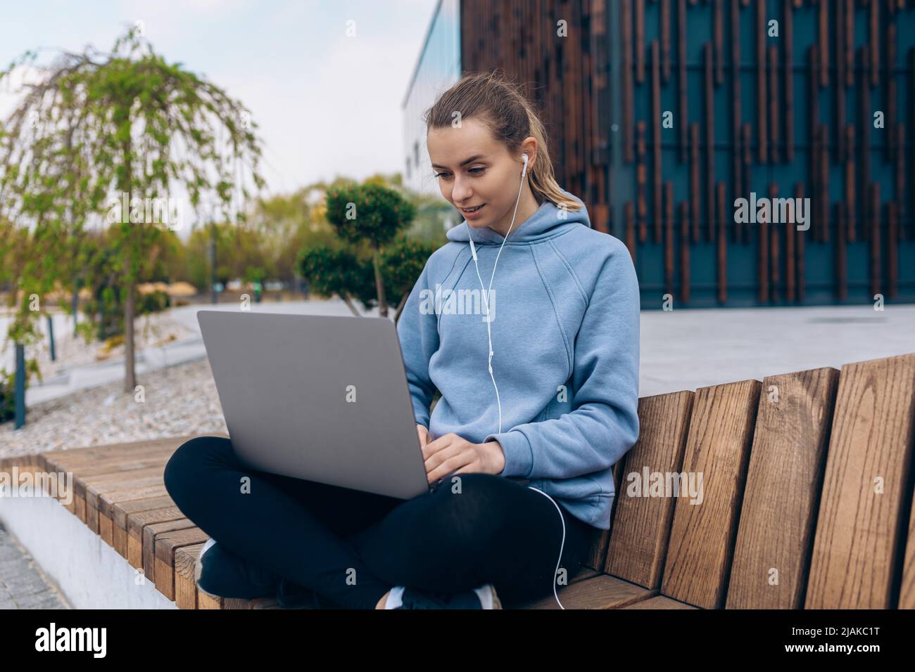 Girl with ponytail sitting with crossed legs, talking using webcam ...