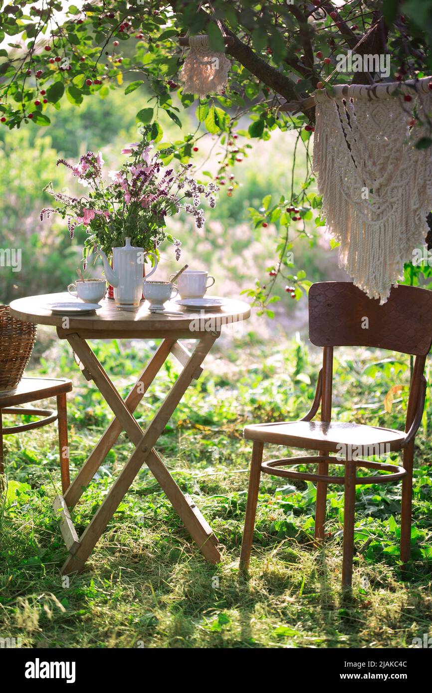 tea party in the garden. on the table is a vase of flowers, pie with ...