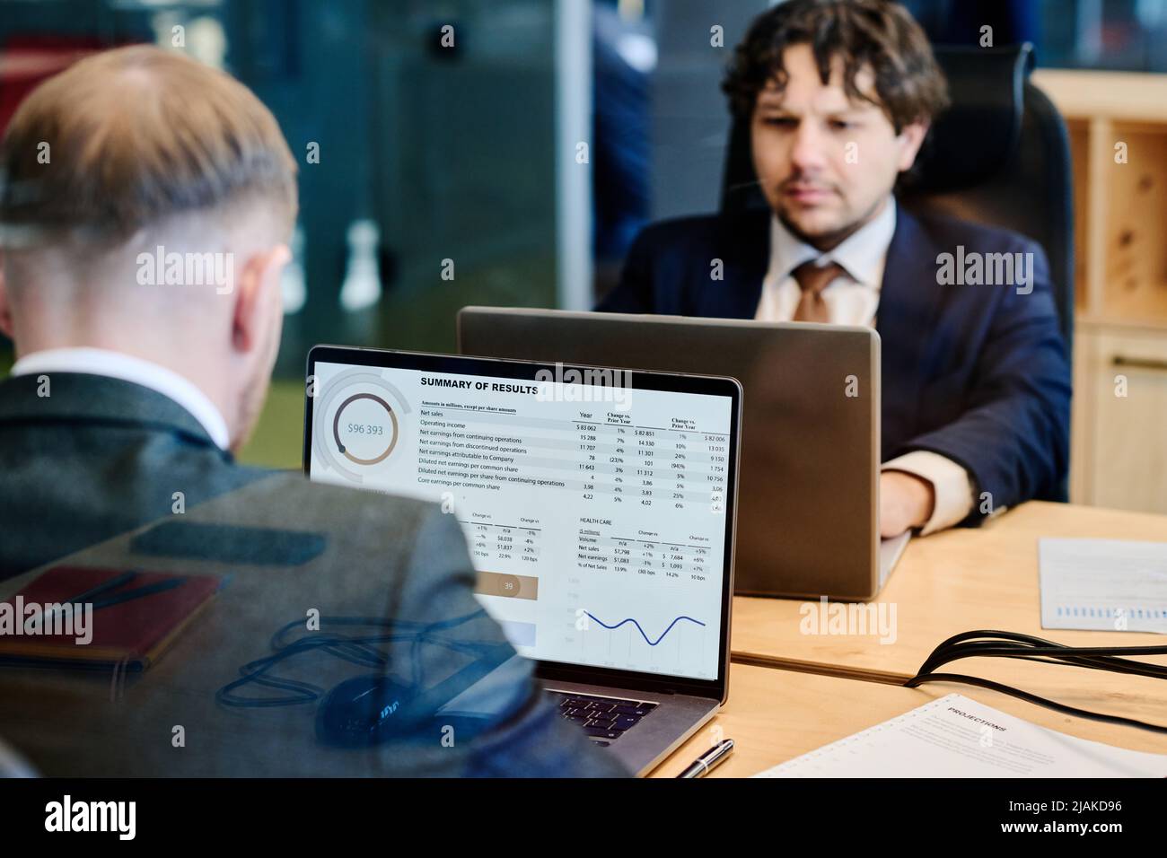 Serious business people examining financial marketing on laptop with ...